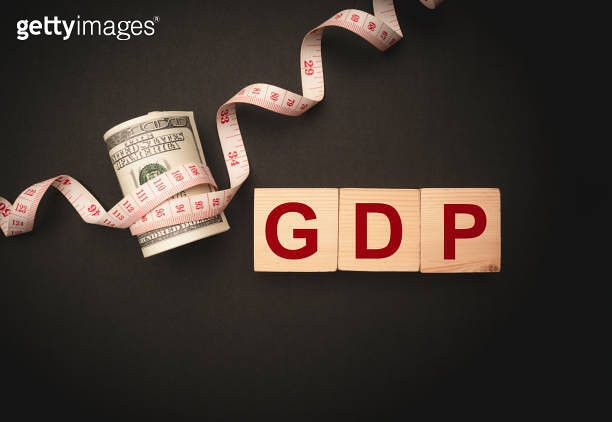 GDP on wooden cubes and a tape measure wrapped around a US dollar ...