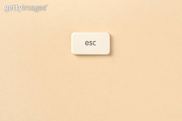 Close-up of an Escape symbol button on a beige background, symbolizing ...