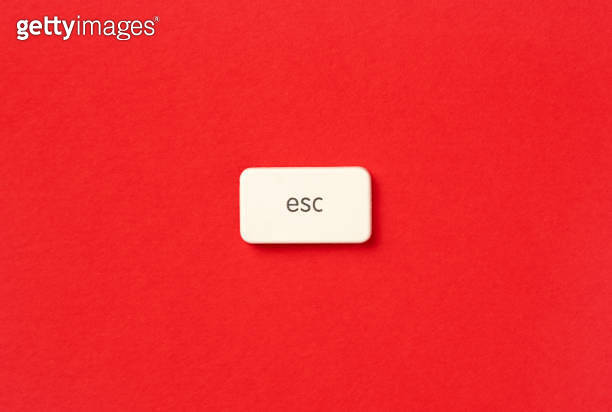Close-up of an Escape symbol button on a vibrant red background ...