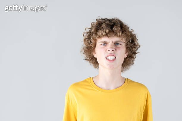 Portrait of curly-haired man with contorted face, baring his teeth in ...