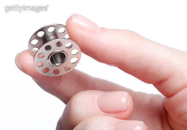 Clear sewing machine bobbins spool in hand 이미지 (2022341111) - 게티이미지뱅크