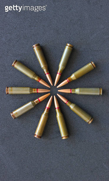 Combat bullets laid out in a circle shape on a black surface vertical ...