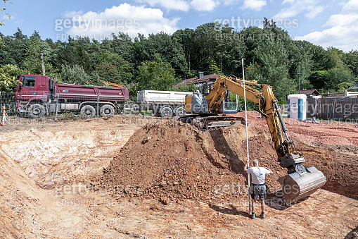 large digger digs a hole for the cellar of a family house,the worker ...