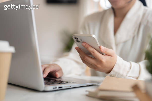 A businesswoman working remotely from a cafe, working on her laptop ...