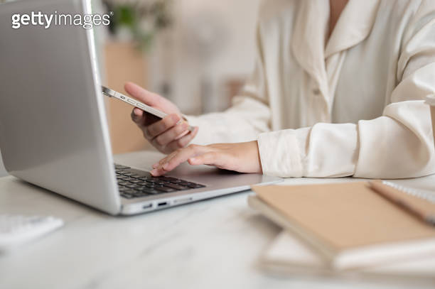 A businesswoman working remotely from a cafe, working on her laptop ...