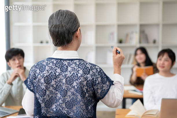 A back view image of a teacher professor giving a lecture to her ...