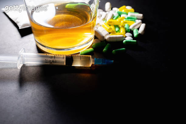Hard drugs and alcohol on dark gray table. Alcohol pills syringe ...