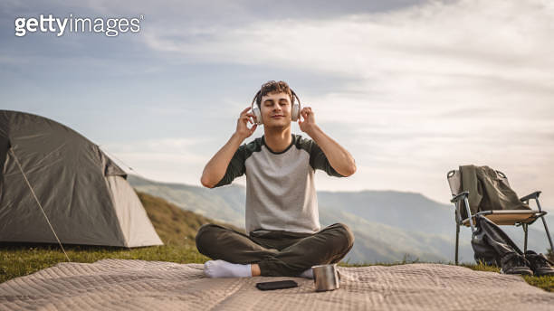 Young boy sit on blanket on the mountain listen music on headphones 이미지 ...