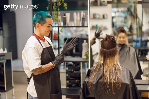 Professional colorist putting on gloves before coloring hair in beauty ...