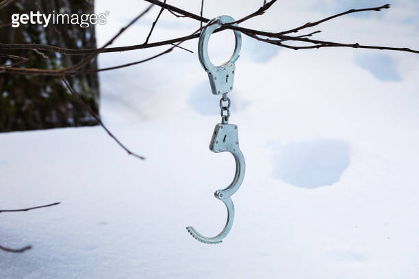 Handcuffs hanging on a branch against the background of footprints in ...