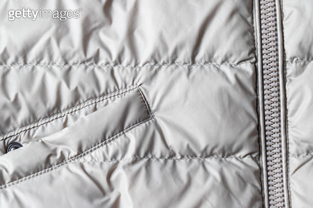 Padded coat in grey color with zipper and pocket. Close up of detail ...