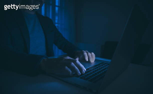 Hands typing on laptop keyboard. Man working on computer. Dark mood ...