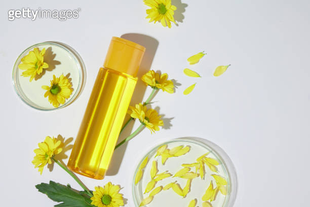 White flat featuring a cosmetic bottle of yellow essence without label ...