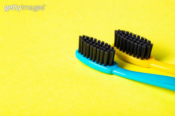 Two toothbrushes with black charcoal hard bristles on a yellow ...