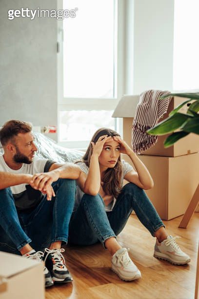 Couple sitting on the floor of their new flat exhausted from moving in ...