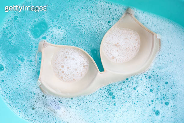 Lady bra soaked in water dissolved detergent with white foam bubble ...