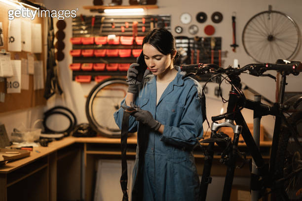 Female mechanic takes order by mobile phone standing in bicycle ...
