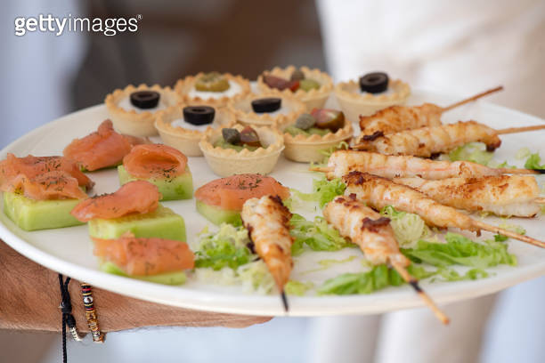 Caterer holding a large plate with small canapes, a selection of finger ...