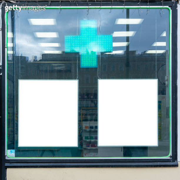 Pharmacy storefront with glowing green cross and two blank ...
