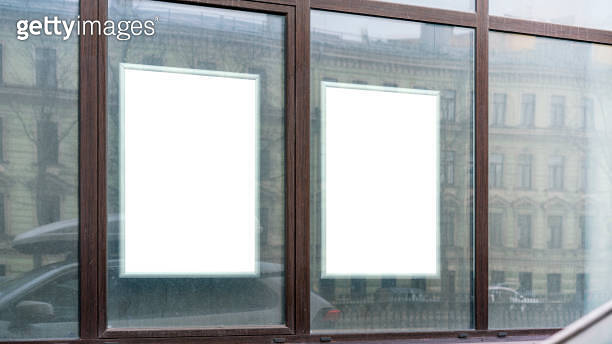 Two blank white posters in wooden frames on glass window with ...