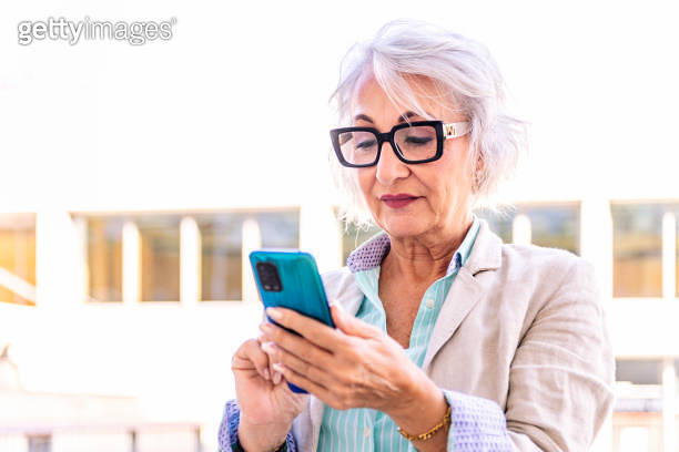 mature woman smiling happy typing on mobile phone 이미지 (2162043534) - 게티 ...