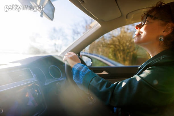 Driving in sunny morning. Ginger woman driving a car with sunlig 이미지 ...