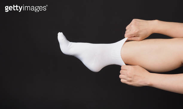 Asian Male legs wear white sock and hand is pulling a sock on black ...