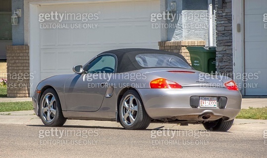 A silver Porsche Boxster convertible parked on a residential street ...