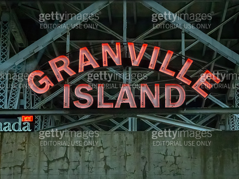 A red neon sign that reads Granville Island mounted on a concrete wall ...