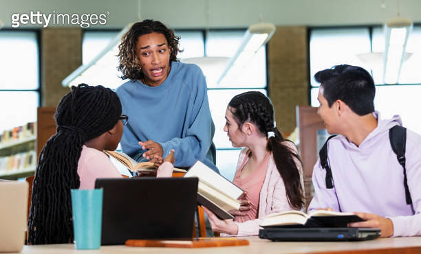 Four multiracial high school students talking in library 이미지 ...
