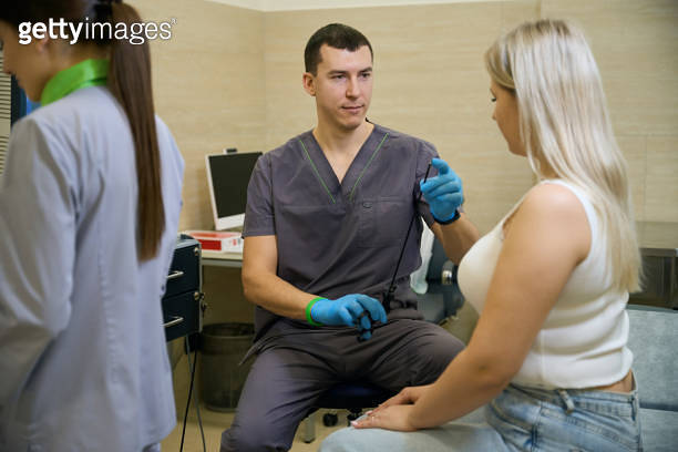 Young proctologist preparing female patient for proctoscopy 이미지 ...