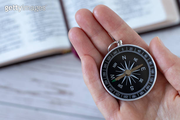 Hand holding compass on top of open holy bible book, close up 이미지 ...