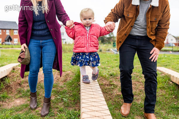 Parents helping baby girl walking on balance beam in park 이미지 ...
