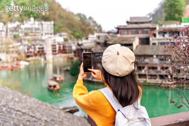 Young female tourist taking a photo of the Feng Huang Ancient Town, The ...