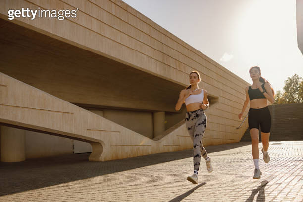 Two active women athlete running on sunny morning side by side on ...