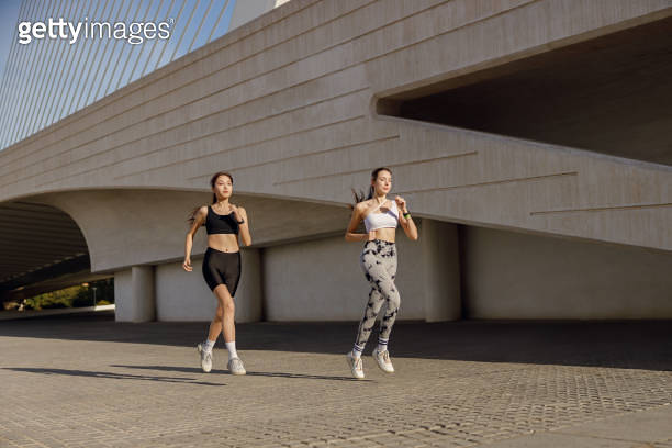 Two active women athlete running on sunny morning side by side on ...