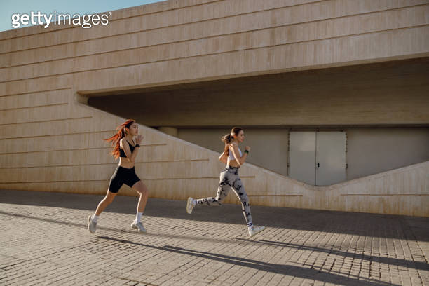 Two active women athlete running on sunny morning side by side on ...