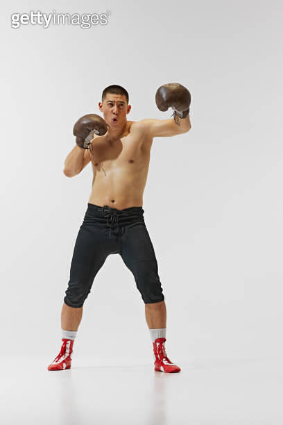 Shirtless emotional young man, young boxer training hard, captured mid ...