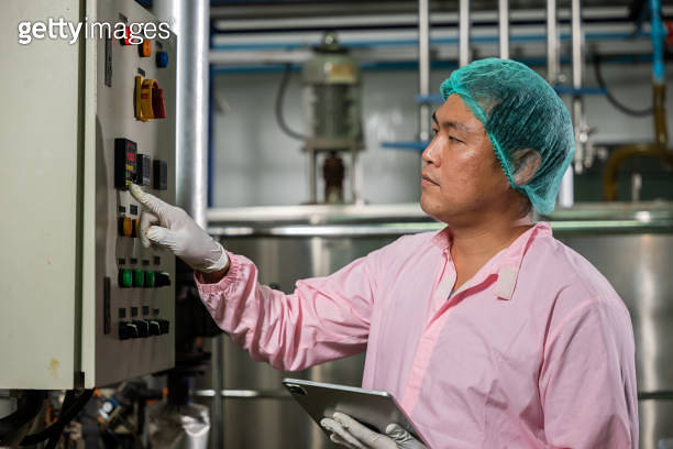 Worker using tablet in beverage factory oversees soda water filling 이미지 ...