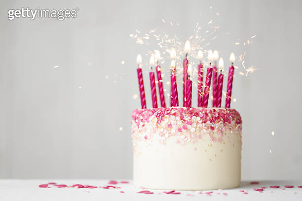 Pink celebration birthday cake with pink birthday candles and sparklers ...