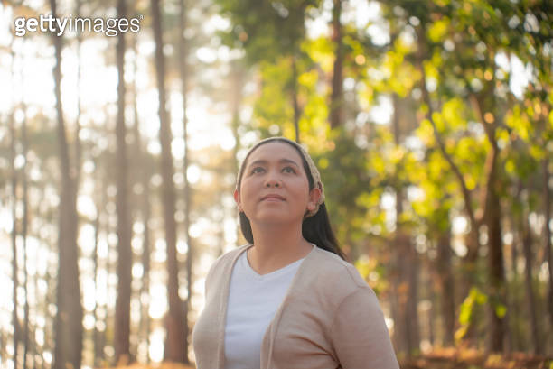 Happy Asian mid-adult woman taking deep breath in the forest, feeling ...