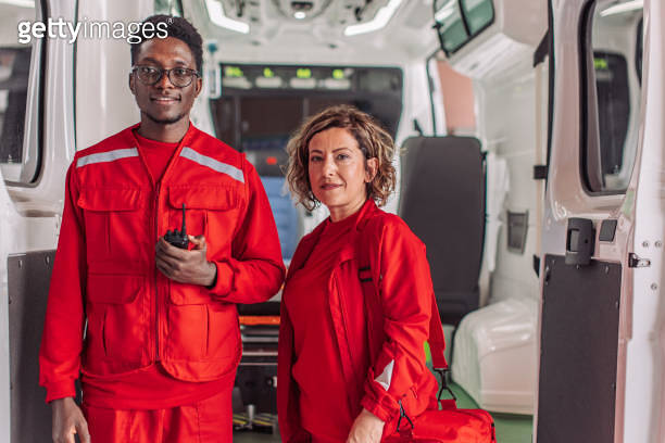 Two paramedics standing inside ambulance holding medical equipment ...