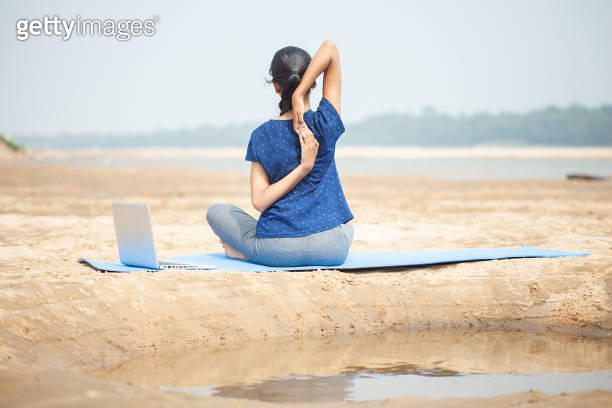 rear view of an athlete girl doing cow face pose or Gomukhasana at a ...