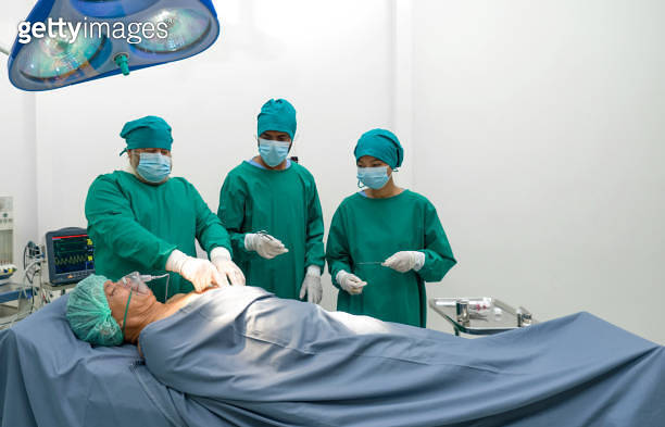 Group of surgeons, steeped in concentration, performing complex surgery ...