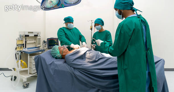 Group of surgeons, steeped in concentration, performing complex surgery ...