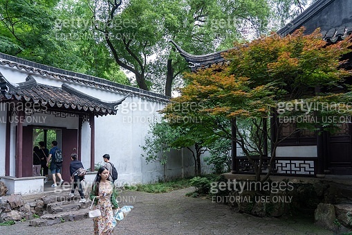 A traditional Chinese garden in Suzhou with a white wall, stone pathway ...