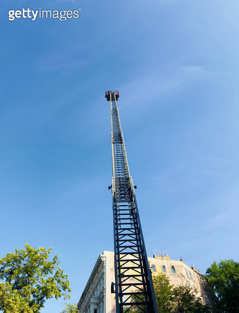 very tall, extended fire truck ladder reaching up into a clear blue sky ...