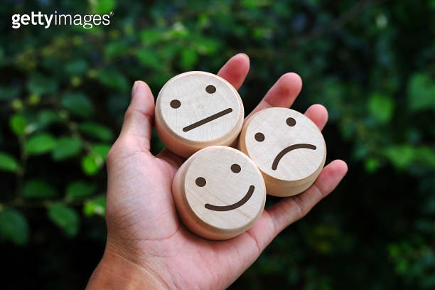 Wooden round with carved happy and angry faces, International Day of ...