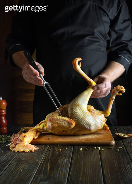 A dish of raw chicken by the hands of a chef in a restaurant kitchen ...