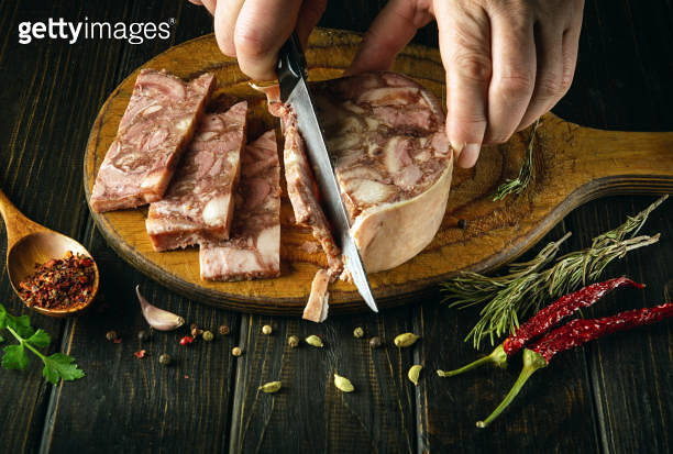The cook cuts the brawn into pieces with a knife on the kitchen board ...